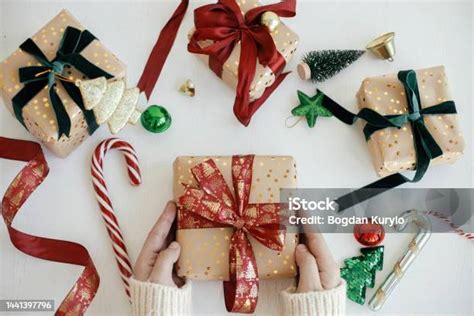 즐거운 성탄절 세련 된 크리스마스 선물 플랫 레이를 들고 손 빨간 리본 황금 포장지 흰색 배경에 장식품으로 현대 선물 상자를 포장하는 사람 대기 겨울철 계절에 대한 스톡