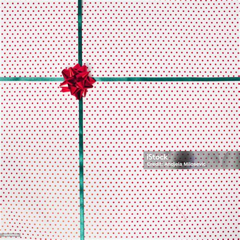 녹색 리본과 빨간색 선물 활은 흰색 배경에 빨간 점이 포장지로 표시됩니다 인사말 메시지를위한 복사 공간이있는 최소한의 현재 개념