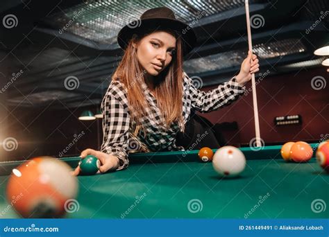 A Girl In A Hat In A Billiard Club With A Cue And Balls In Her Hands Playing Pool Stock Image