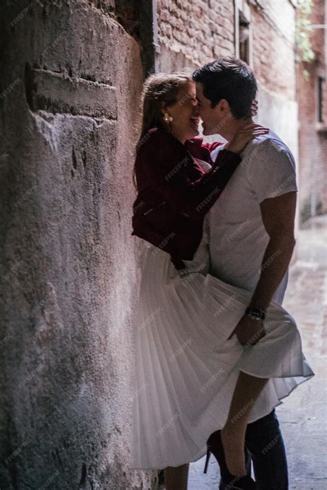 Premium Photo Side View Of Young Couple Kissing Against Wall