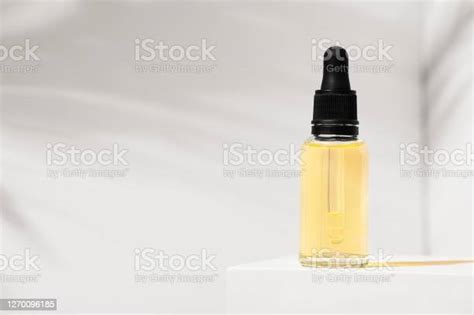 흰색 스탠드에 드롭퍼가 있는 세럼 병과 야자수 그림자가 있는 배경 스킨케어 뷰티 스파 제품 및 파이펫 여성 피부 모발을 위한 유리 패키지 비타민 오일 복사 공간 그림자에