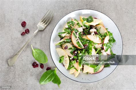 신선한 사과 크랜베리 호두 이탈리아 리 코타 치즈 시금치로 건강 한 과일과 베리 샐러드 나뭇잎 아침 식사 맛 있는 고 영양가 있는 식단 요리입니다 샐러드 그릇에 회색 돌