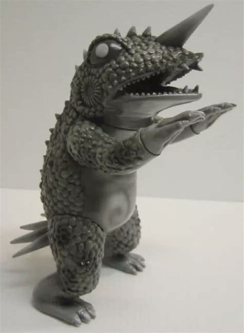 A Toy Godzilla With Its Mouth Open And Its Legs Spread Wide On A