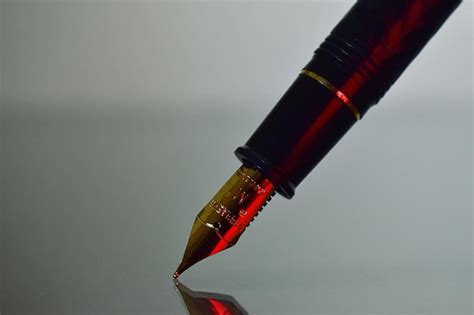 A Hand Holds A Pen Hovering Above Lined Paper Pen Tip Touching But Not
