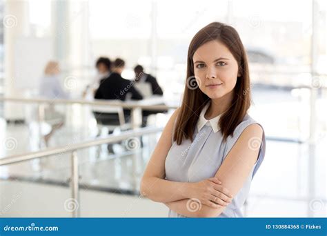 Portrait Of Millennial Female Employee Posing With Arms Crossed Stock