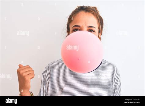Young Redhead Woman Chewing Gum And Blowing Hair Bubble Over White Isolated Background Pointing