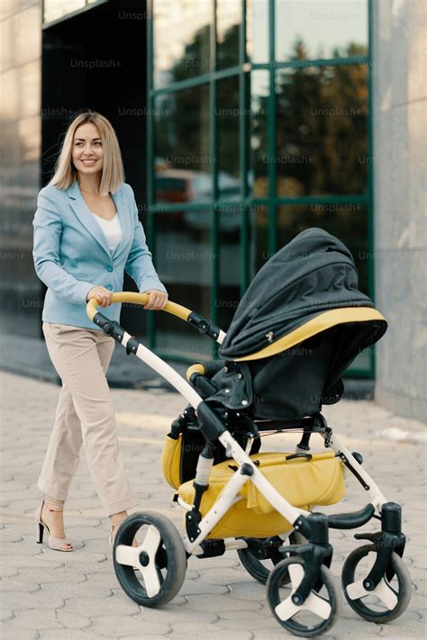 아기와 함께 파란색 정장을 입은 성공적인 비즈니스 여성의 초상화 유모차를 밀고 있는 사업가 여자 사진 Unsplash의 작다 이미지