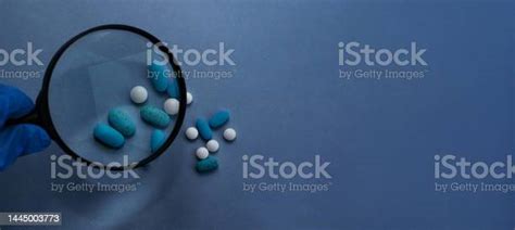 의사의 직장 흩어진 알약과 가벼운 배경에 최고 보기 파란색 의료 장갑을 낀 의사가 돋보기를 손에 들고 있다 의료 개념 0명에 대한 스톡 사진 및 기타 이미지 Istock