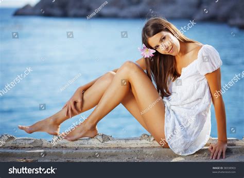 Portrait Of Beautiful Brunette Woman With Long Legs Posing Over Sea