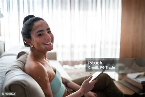Potret Seorang Wanita Muda Menggunakan Smartphone Yang Duduk Di Sofa Di