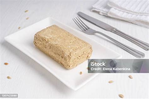 하얀 나무 테이블에 포크와 칼로 먹을 준비를 한 해바라기 씨와 설탕으로 만든 할바 달콤한 디저트 전체 조각 할바에 대한 스톡 사진 및 기타 이미지 Istock