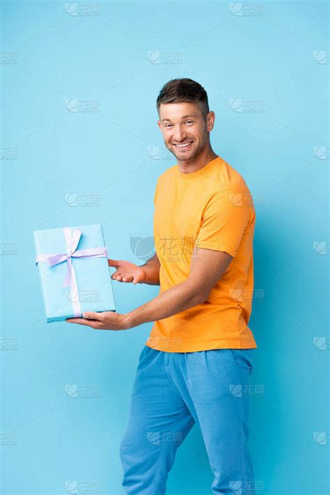 穿着t恤的快乐男人拿着蓝色包装的礼品盒