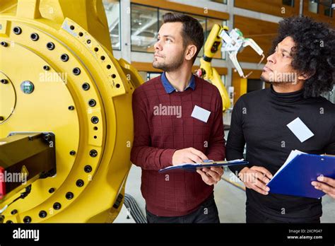 Two Engineers Reviewing And Programming Multi Purpose Robotic Arms In A