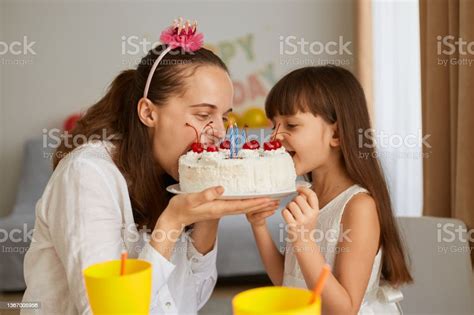 테이블에 앉아 맛있는 케이크를 물어 생일을 축하 긍정적 인 축제 감정을 표현 집에서 실내 포즈와 함께 행복한 여자의 실내 샷 2