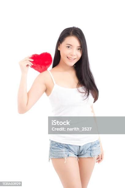 빨간 심장 모양 베개와 흰색 배경에 고립 된 미소를 들고 아름 다운 아시아 젊은 여자의 초상화 발렌타인 데이 휴일 개념 개념에