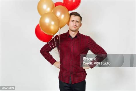 잘생긴 백인 슬픈 화가 젊은 Y 남자 흰색 바탕에 생일을 축 하 하는 노란색 황금 풍선 빨간색 격자 무늬 셔츠에 2530 년 광고에 대 한 고립 휴일 파티 개념입니다