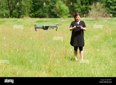 Young Smiling Woman Pilot Operating The Drone By Remote Control Flying