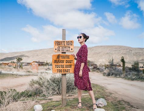 분홍색과 흰색 긴팔 드레스를 입은 여자가 낮 동안 도로 표지판 옆에 서 있다 사진 Unsplash의 무료 갈색 이미지