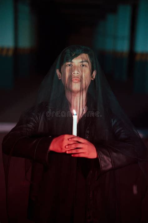 A Man Dressed All In Black Holding A Candle When Going To A Cemetery To