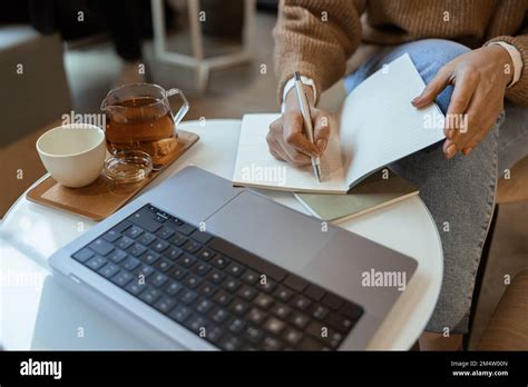 Close Up Of Woman Making Notes In Notepad While Working Laptop In Cafe Stock Photo Alamy
