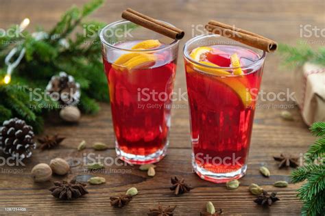나무 테이블에 계피 막대기로 장식 된 유리 잔의 멀드 와인은 근처의 녹색 가문비 나무 가지 콘입니다 크리스마스 음료 새해 펀치
