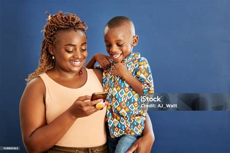 파란색 배경에 대해 아들과 함께 전화를 사용하는 웃는 여자 어머니에 대한 스톡 사진 및 기타 이미지 어머니 아이 여자