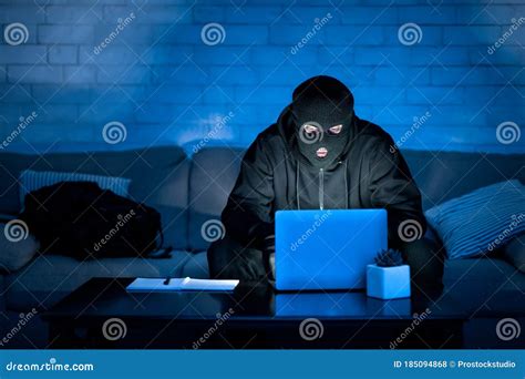 Masked Hacker Downloading Private Information Off A Computer Stock