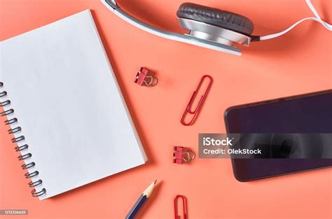 스마트 폰 또는 태블릿 빈 종이 메모장 및 오렌지 배경에 다른 문구 물건 근처 현대 흰색 헤드폰 콜 센터 개념입니다 공간을
