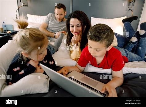 Parents And Girl With Boy Using Laptop On Bed In Hotel Room Stock Photo Alamy