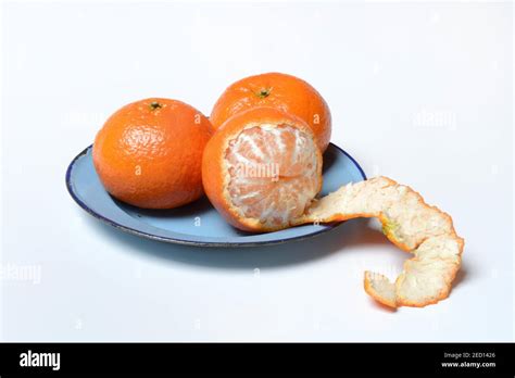 Clementines On Plate Unpeeled And Half Peeled White Background