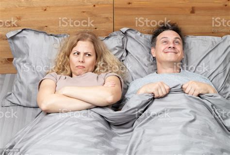 행복한 남자와 불만을 품은 여자는 덮개 아래 침대에 누워 관계 개념 2명에 대한 스톡 사진 및 기타 이미지 2명 40 49