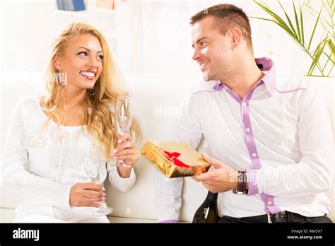Happy Young Man Gives His Cute Girlfriend A T In Home Interior Stock
