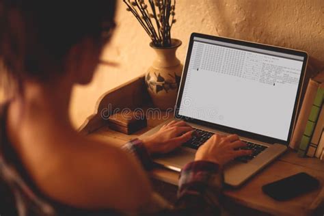 Back View Of Caucasian Female Programmer Siting At Desk Using Laptop With Coding On Screen