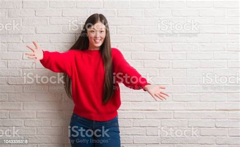 포옹에 대 한 두 팔을 벌려 웃 고는 카메라를 보고 하는 벽돌 벽을 통해 젊은 중국 여자 명랑 식 수용 행복입니다 겨울에 대한