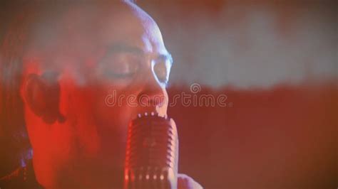 Man Singing Into Retro Microphone On Music Stage Amid Red Haze Overlaying Animated Wave Charts