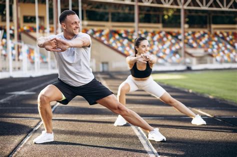 Mujer Y Hombre Estirándose En El Estadio Antes De Trotar Foto Premium