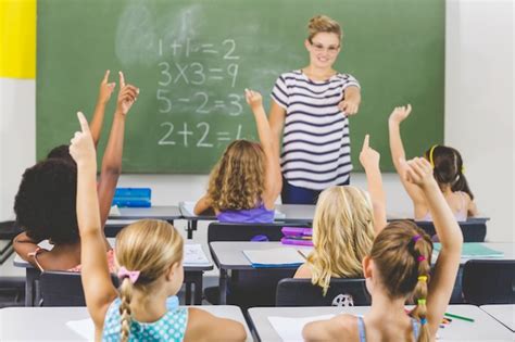 Crianças da escola levantando a mão na sala de aula Foto Premium