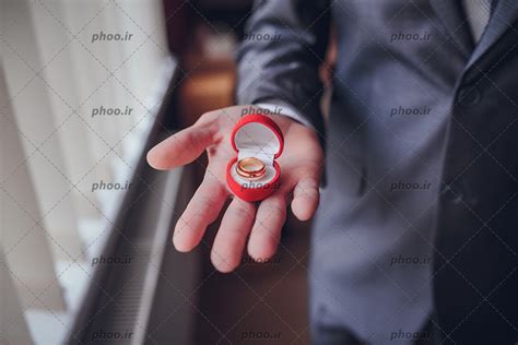 عکس با کیفیت حلقه طلایی در جعبه در دست مرد با کت مشکی عکس با کیفیت و تصاویر استوک حرفه ای