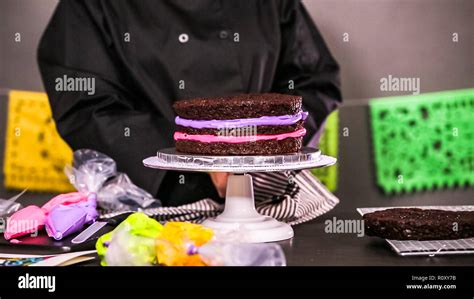 Step By Step Baker Assembling A Chocolate Cake With Bright Colorful Buttercream Frosting For