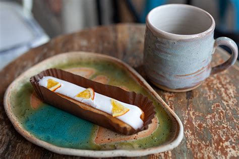 카페의 질감이있는 나무 테이블에 흰색 유약과 접시와 찻잔에 말린 오렌지 조각으로 장식 된 아름다운 Éclair 감귤류 과일에 대한 스톡 사진 및 기타 이미지 Istock