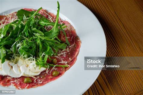 Tonnato Vitello Segar Dengan Jamur Arugula Dan Parmesan Di Atas Piring