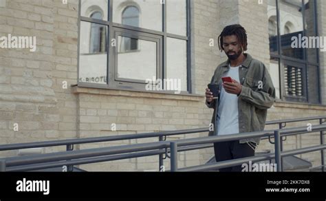 Handsome Mixed Race Man With Dreadlocks In Casual Clothes Scrolling