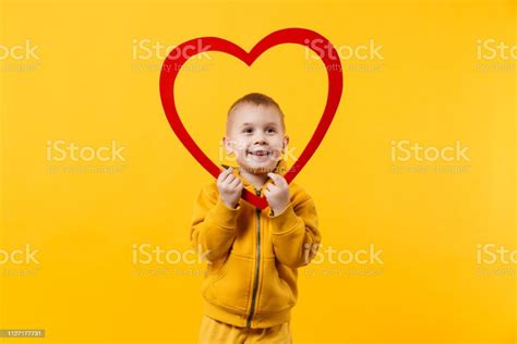 리틀 아이 보가 34 년 된 노란색 옷을 입고 오렌지 벽 배경 어린이 스튜디오 초상화에 고립 된 붉은 마음 잡으십시오 사람들이 진심으 감정 어린 시절 라이프 스타일 개념