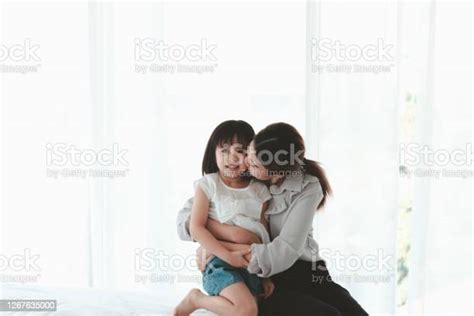 침실에서 즐거운 가족 어머니 딸 함께 시간을 보내고 침대에서 엄마와 놀고있는 어린 소녀 엄마키스 부모와 아이는 집에서 함께 좋은