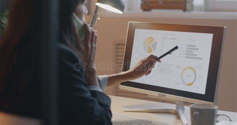 Female Employee Discussing Business During Mobile Phone Call And Pointing At Information On