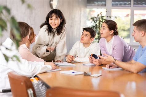Young Teacher Discussing Her Notes With Students Around The Table Stock Young Teacher Discussing Her Notes With Students Around The Table Stock