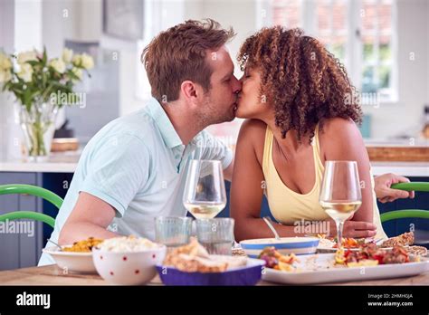 Kissing Couple Having Romantic Meal At Home On Date Night Together