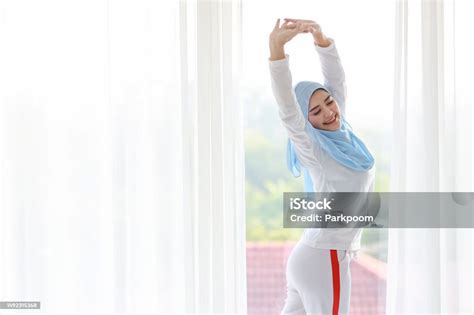 하얀 무슬림 잠옷을 입고 일출에 아침에 일어난 후 팔을 뻗는 아름다운 아시아 여성 파란 히잡을 쓴 귀여운 소녀가 행복하고 웃는