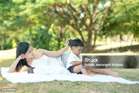 젊은 아시아 의 어머니 휴식 에 거짓말 에 화이트 카펫 근처 그녀의 작은 아기 과 그녀의 아들 누구 즐기는 와 휴대 전화 와