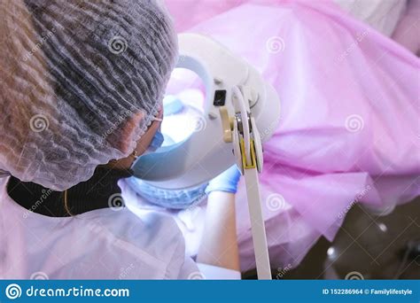 Cosmetologist Op Het Werk Behandelt De Huid Van De Pati Nt Met Een Groot Gloeiend Vergrootglas